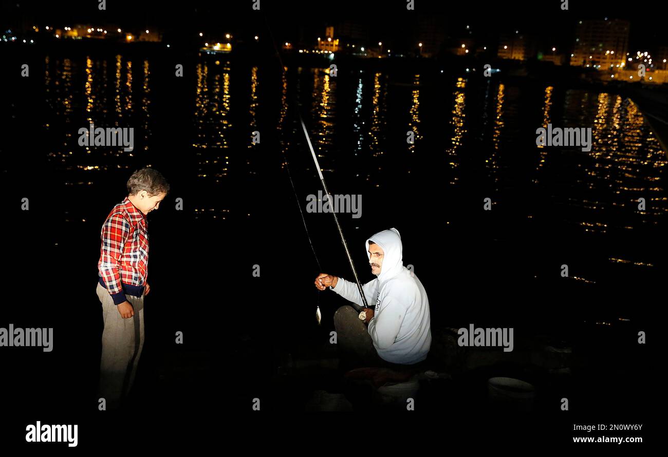 A Palestinian man catches a fish with a fishing rod from the basin at ...