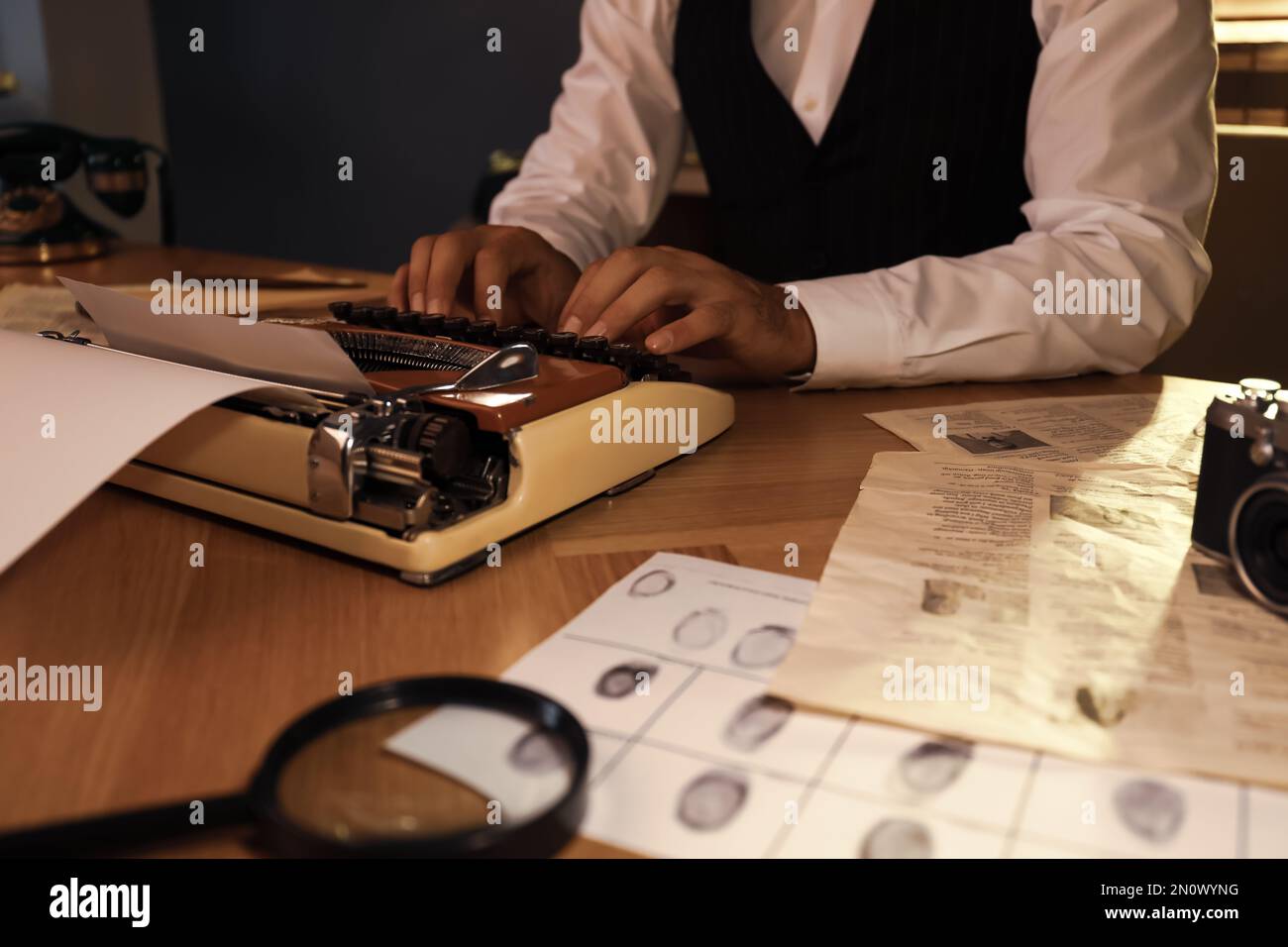 Old fashioned detective working with typewriter at table in office ...