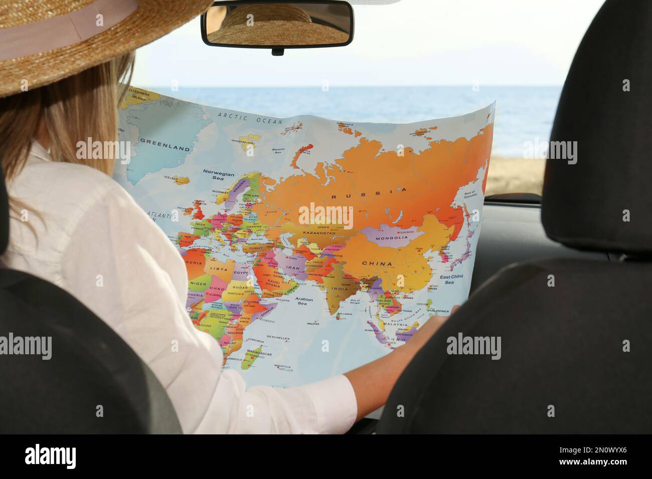 Young woman with world map in car, back view. Road trip Stock Photo - Alamy
