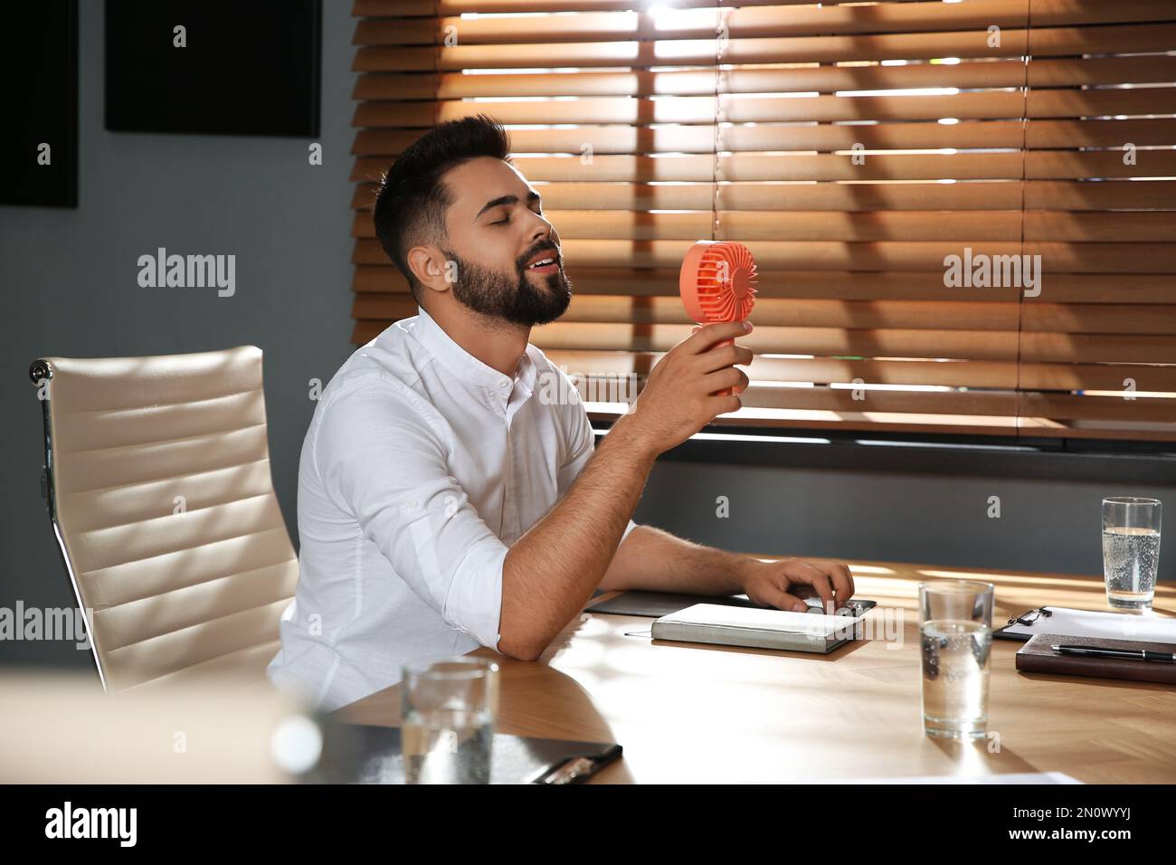 Man enjoying air flow from portable fan at workplace. Summer heat Stock ...
