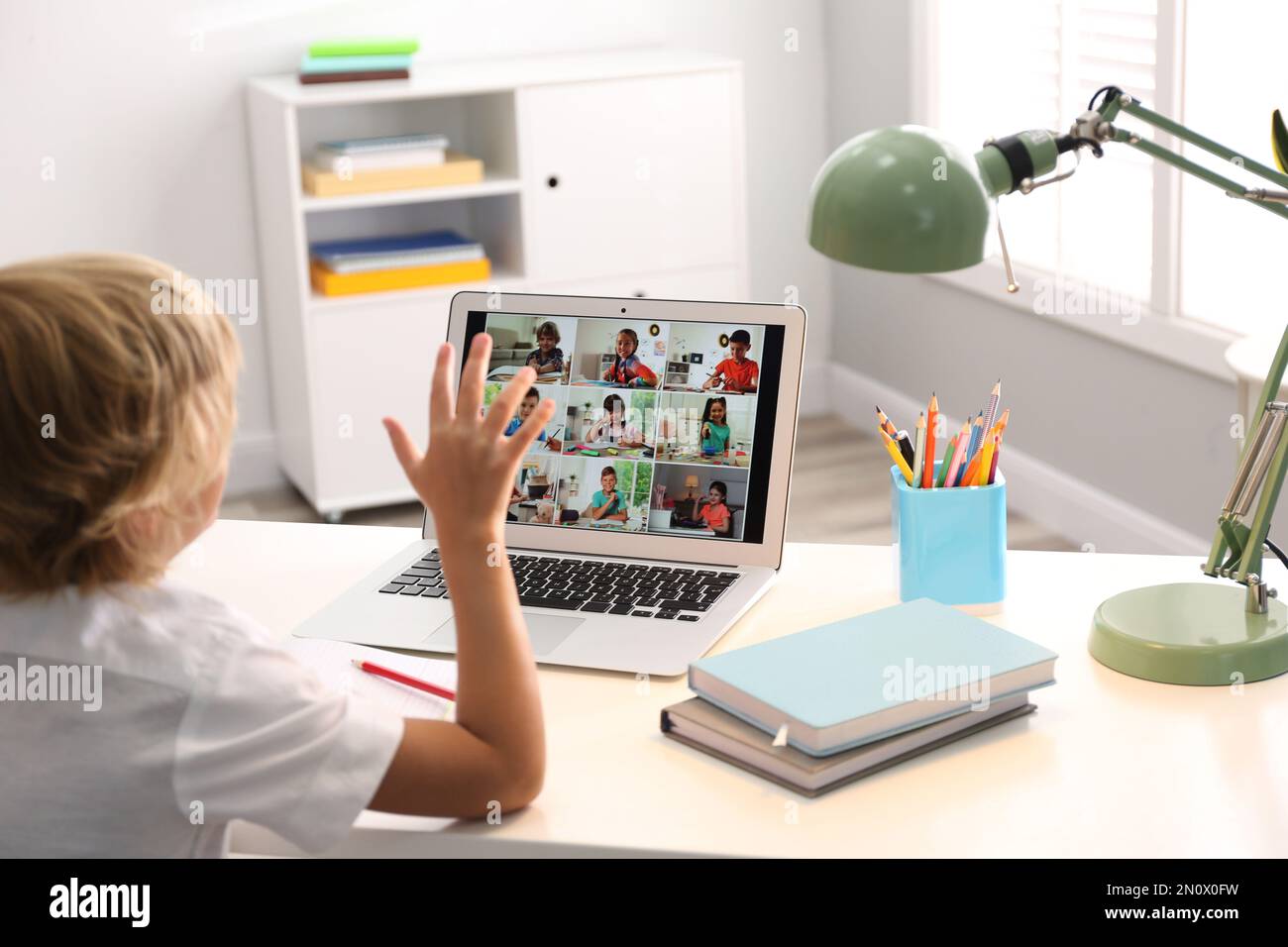 Little boy studying with classmates via video conference at home ...