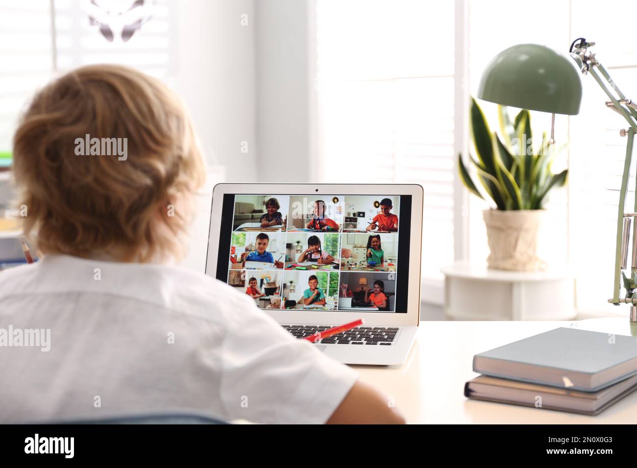 Little boy studying with classmates via video conference at home ...