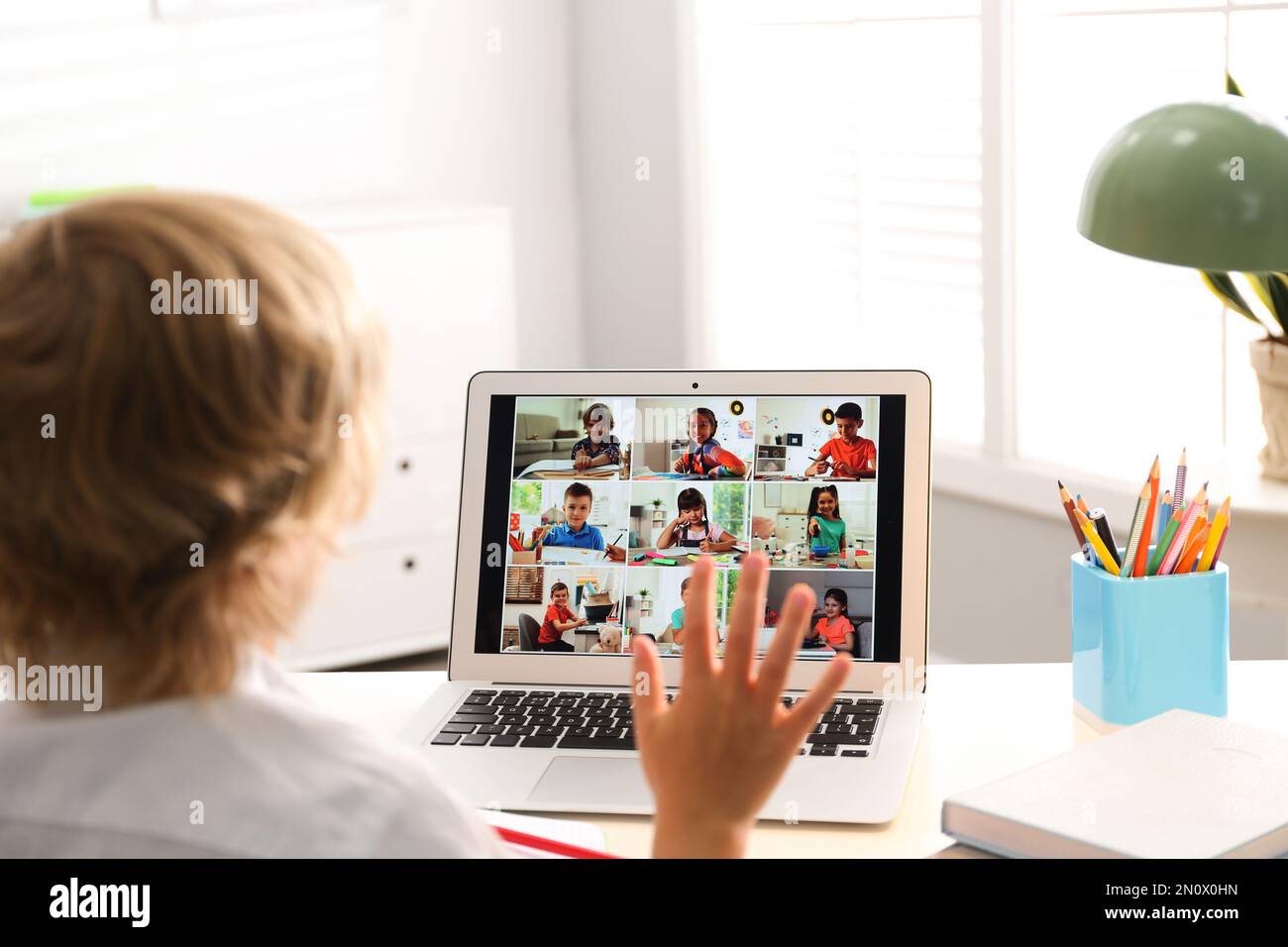 Little boy studying with classmates via video conference at home ...