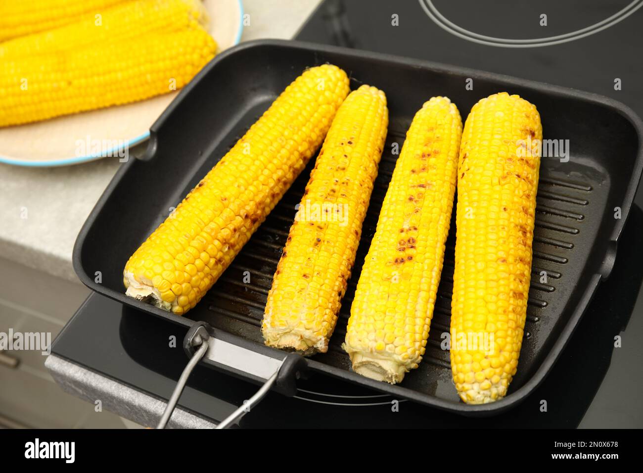 Cooking fresh corn cobs on grill pan, closeup Stock Photo - Alamy
