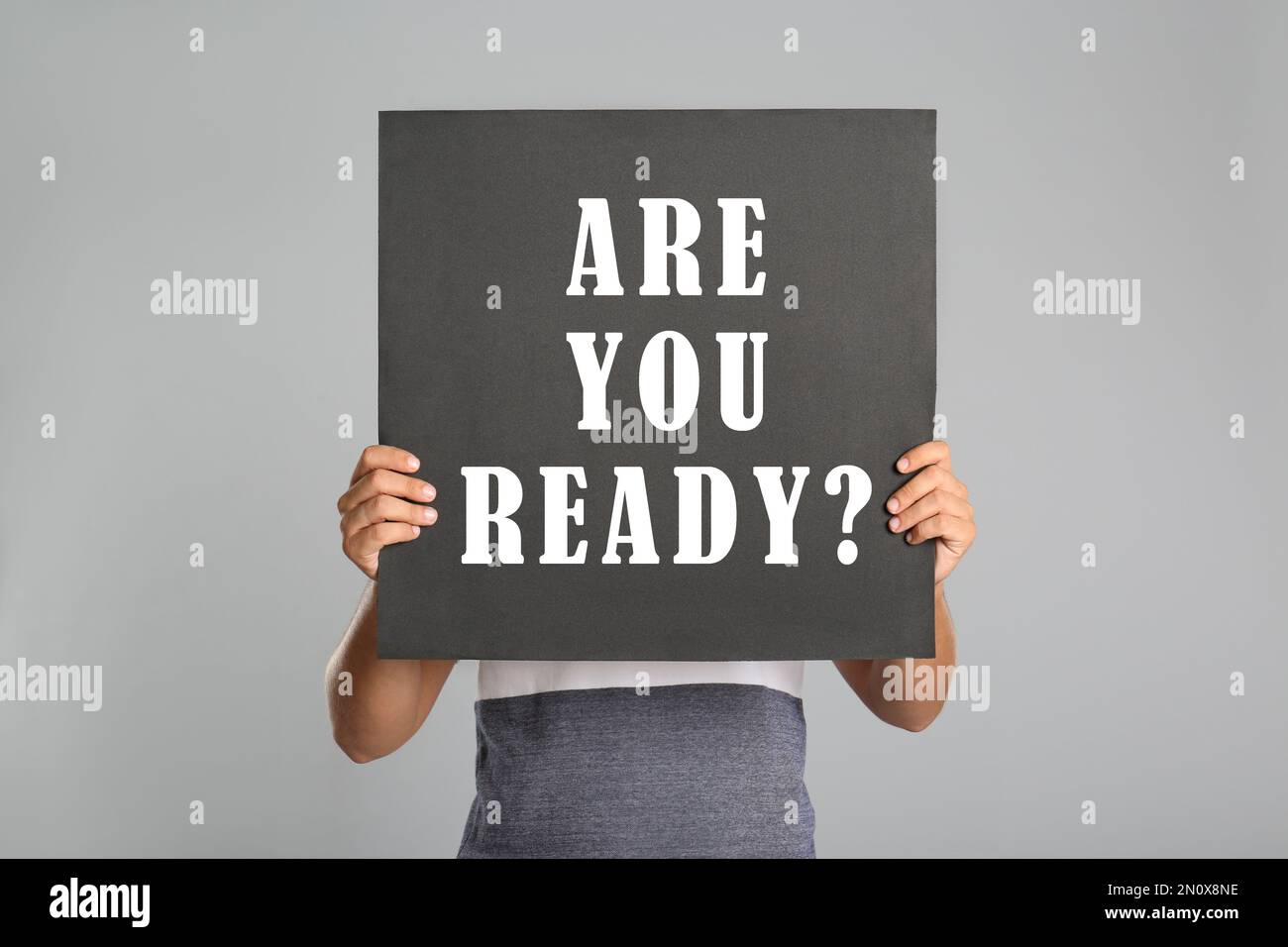 Man holding poster with text Are You Ready? on light grey background ...