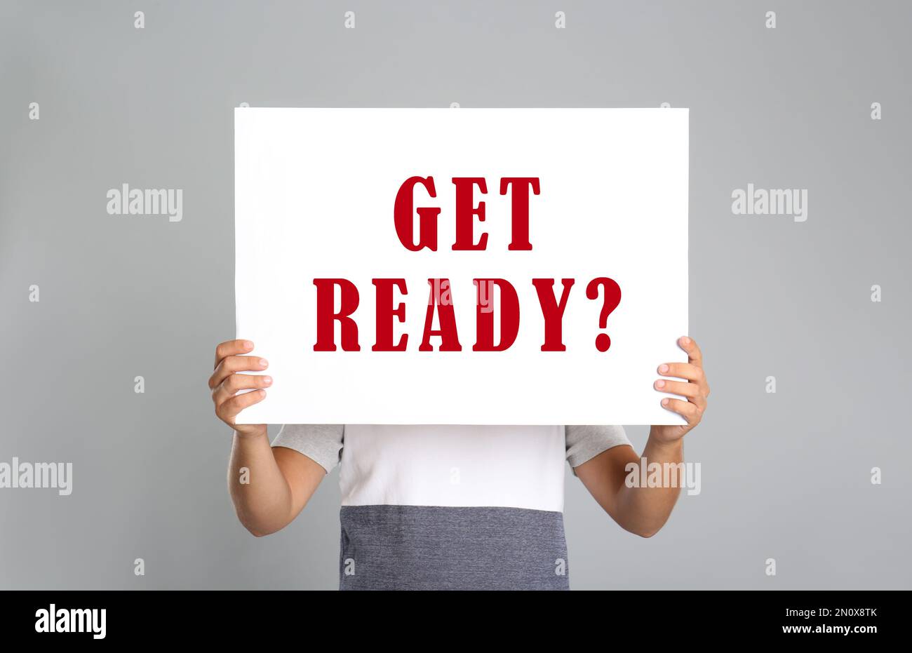 Man holding poster with text Get Ready? on light grey background Stock ...