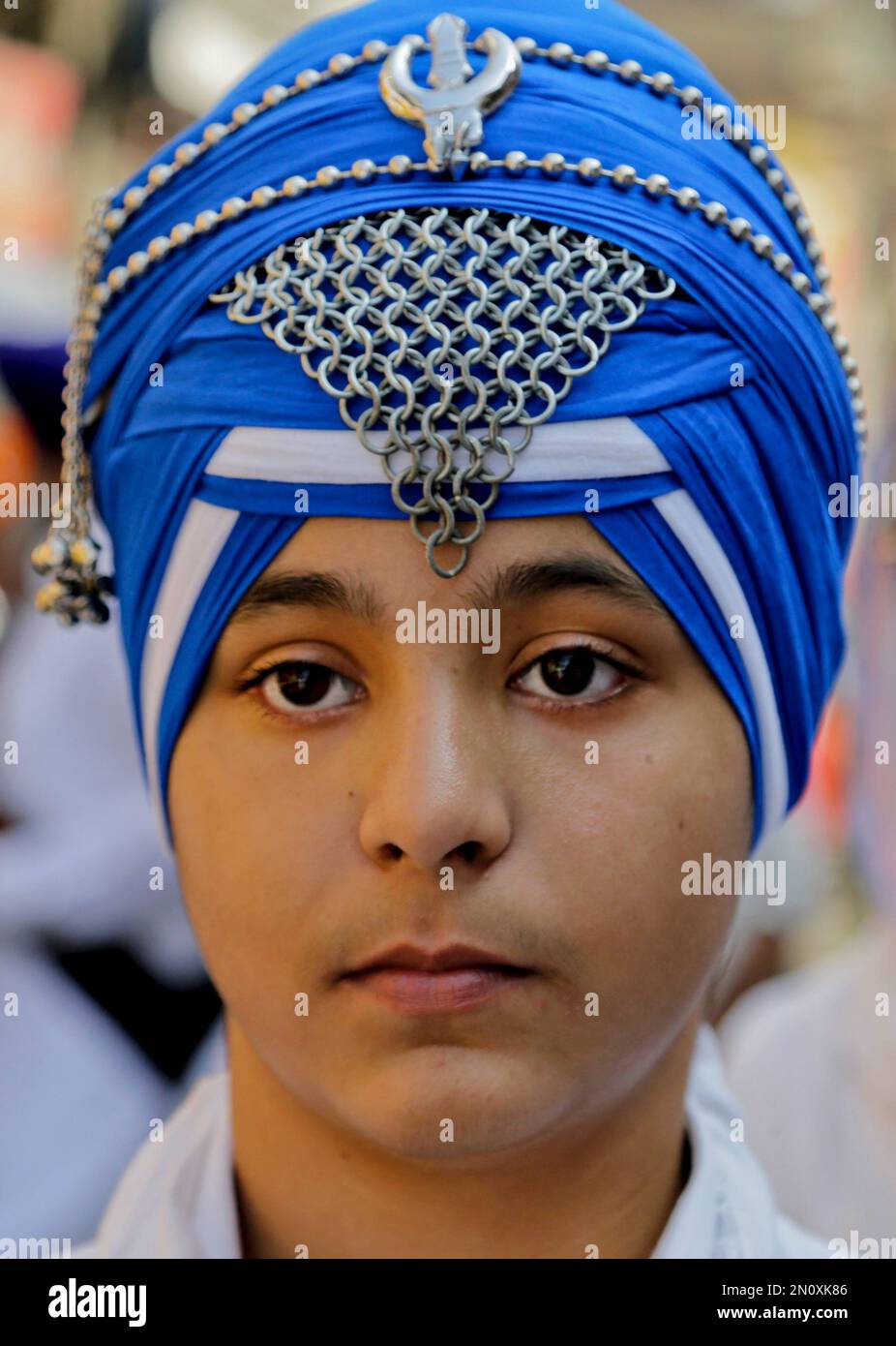 A Sikh boy in a traditional attire has religious symbols on his ...