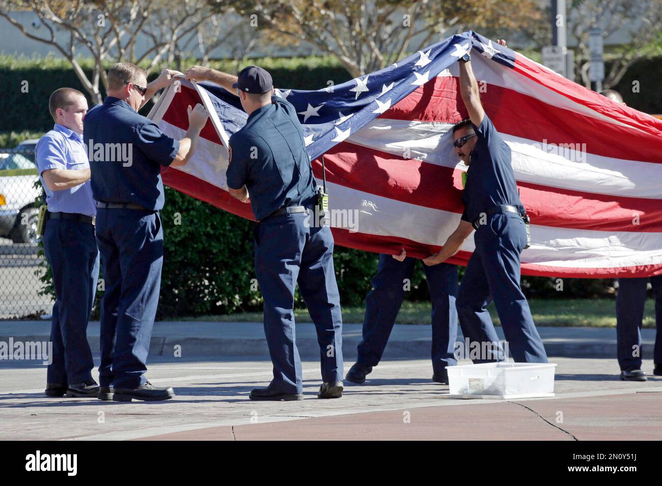 Downey, Calif., city firefighters furl a large American flag that had ...