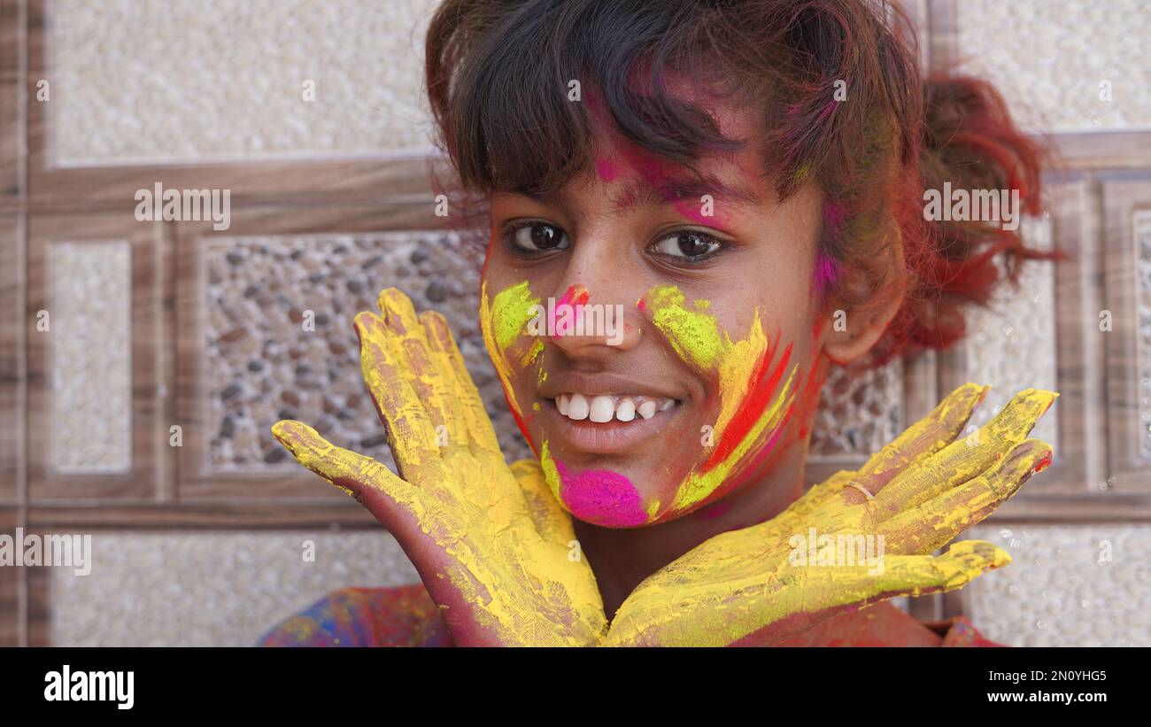 Beautiful young girl posing with exploding pink and yellow Holi powder ...