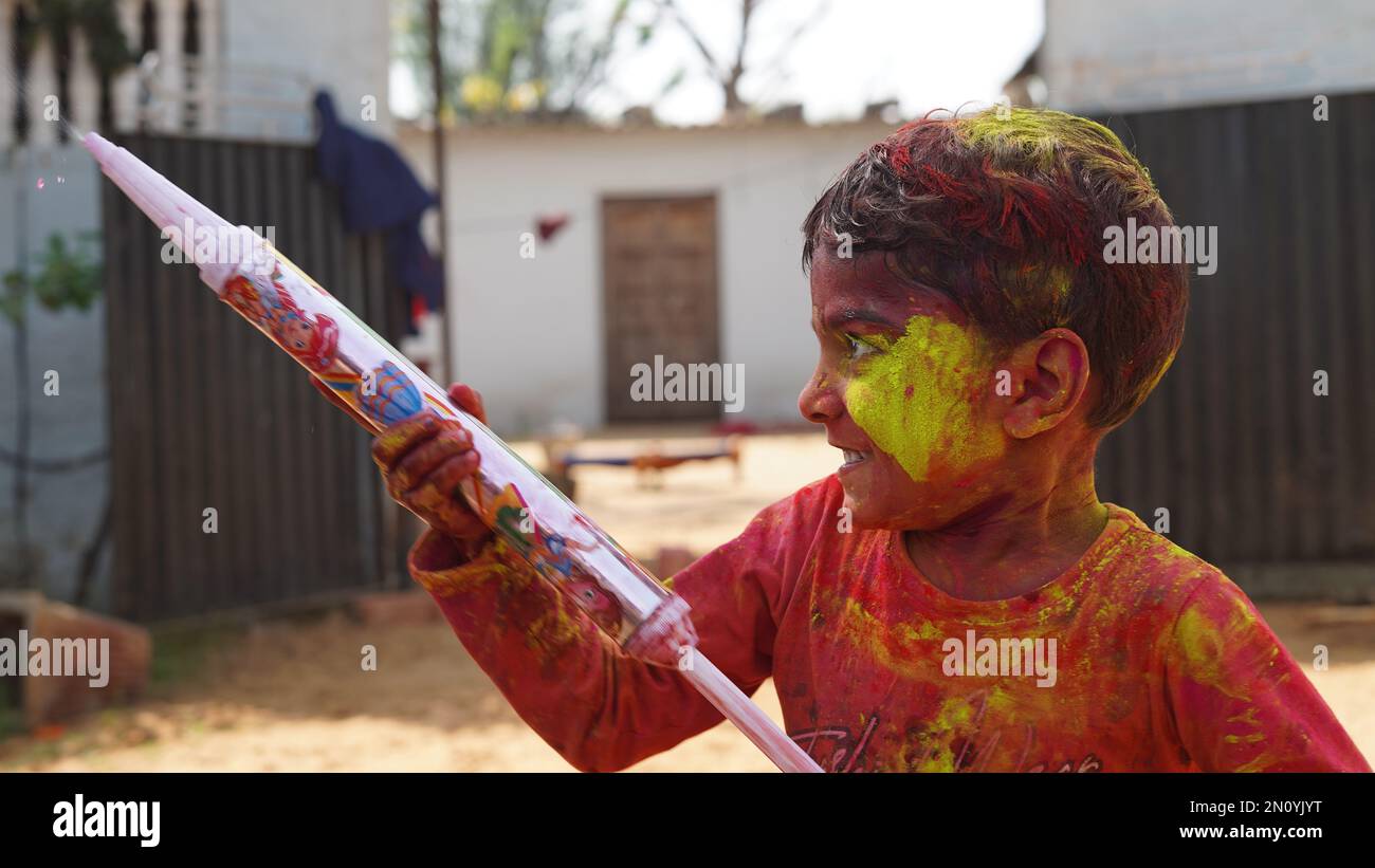 Indian children spray colored with water gun as they celebrate Holi ...