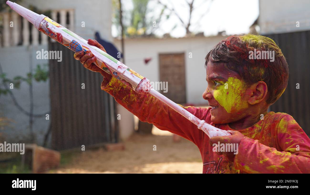 Indian children spray colored with water gun as they celebrate Holi ...