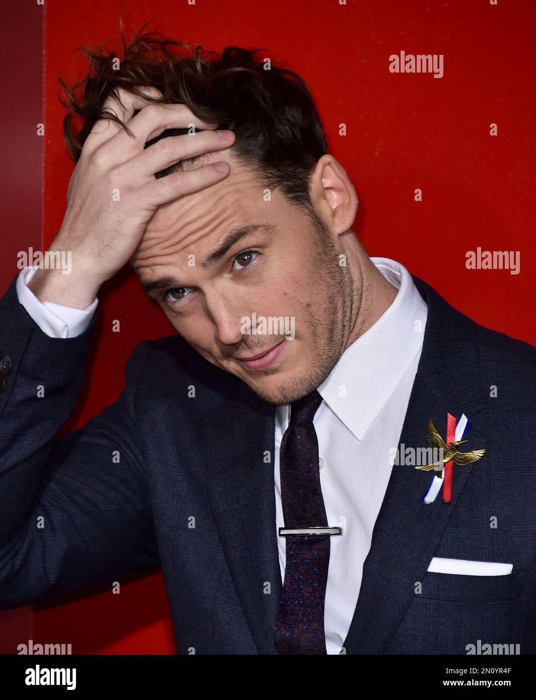 Sam Claflin, wearing a Mockingjay pin with the French tricolor, arrives ...