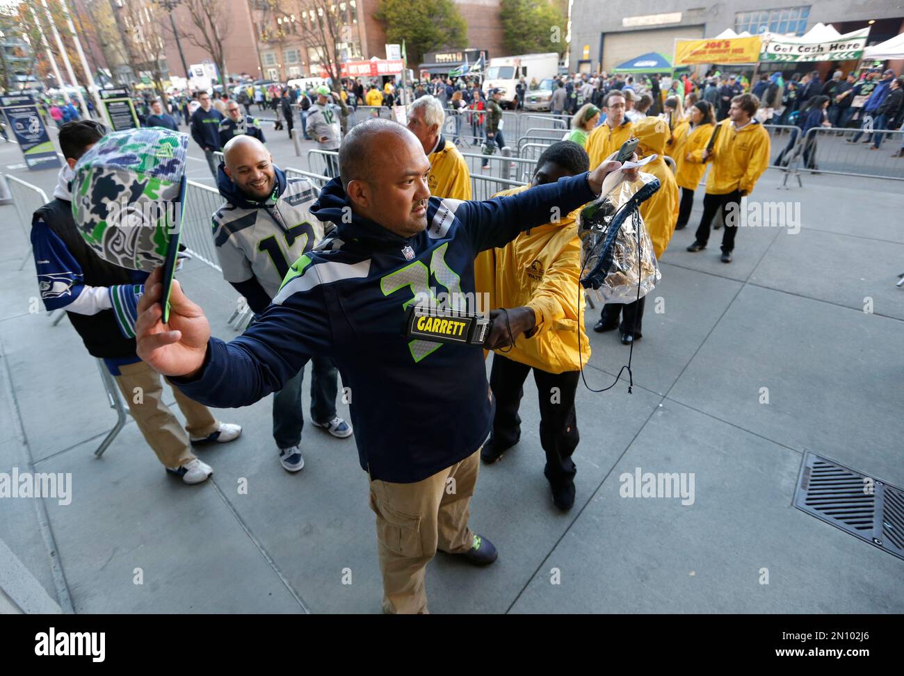 A security official uses a metal detector wand to check a fan arriving ...
