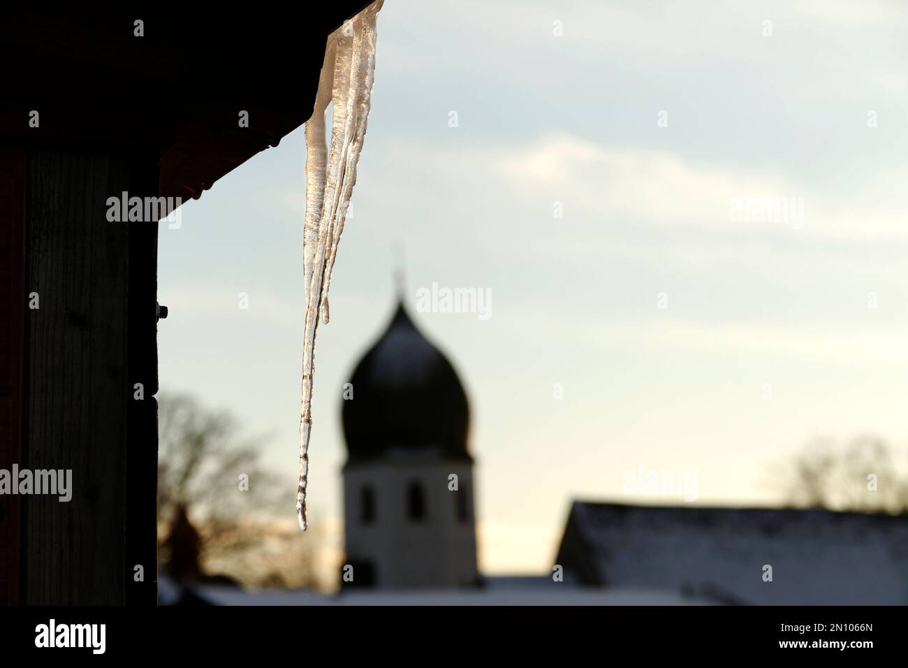 Icicle formation hanging from roof with the Saint Irmingard Church ...
