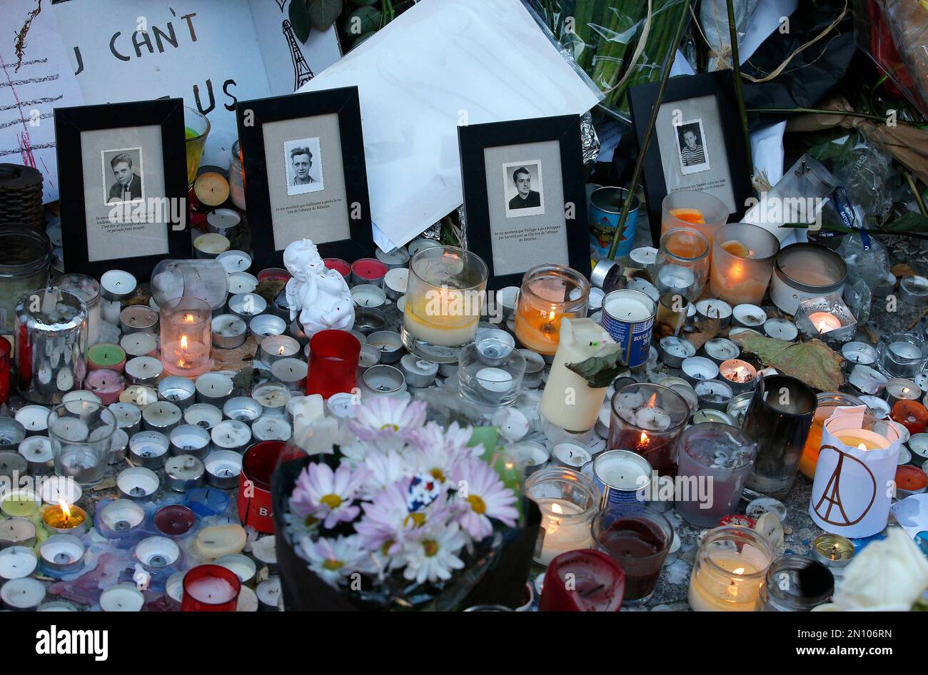 Pictures of victims are placed behind candles outside the Bataclan ...