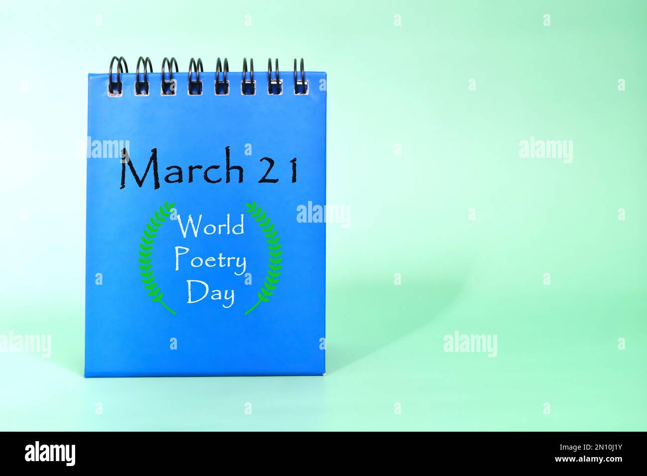 March 21 as World Poetry Day date reminder on blue desk calendar ...