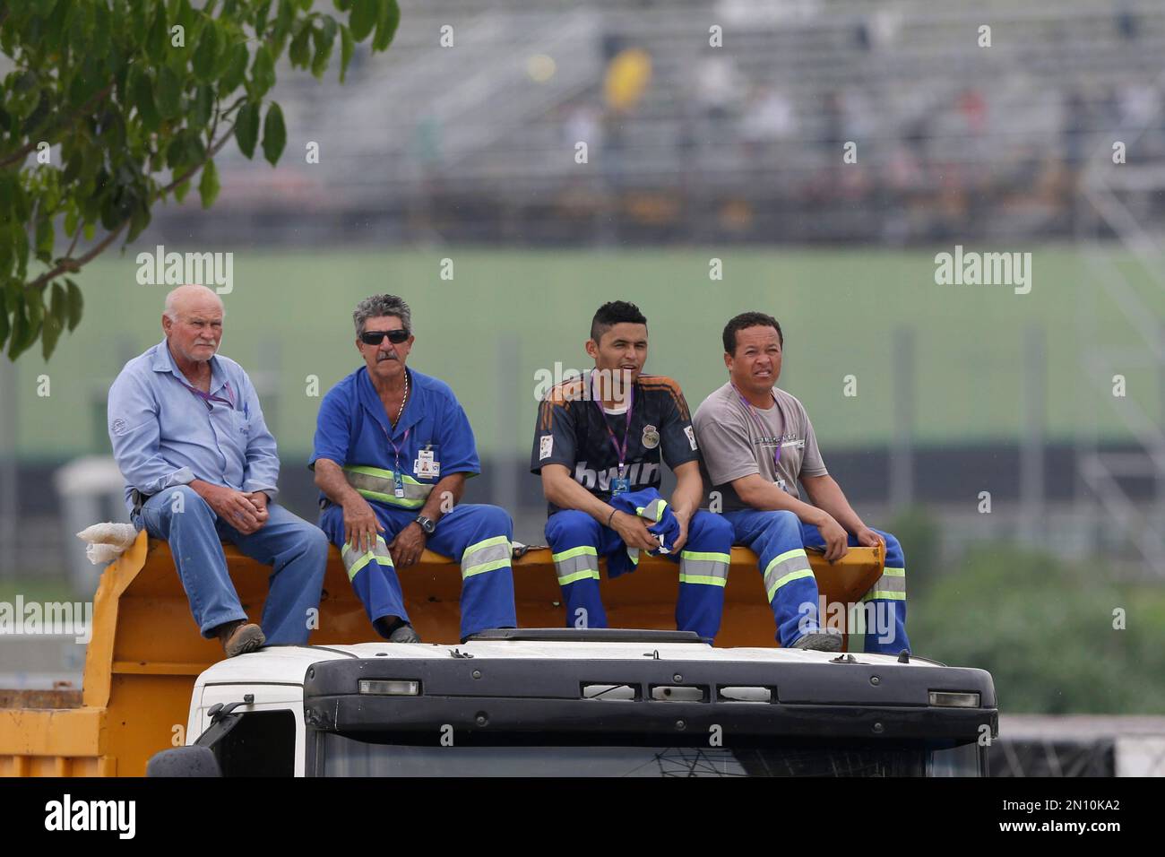 Workers sitting on top of a truck watch the second free practice for ...