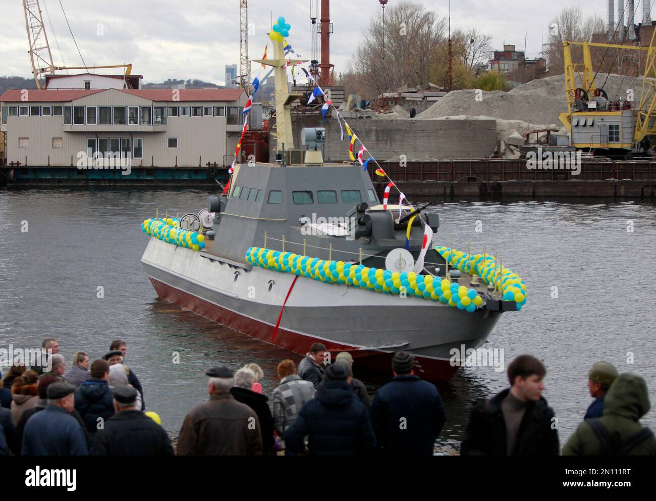 People watch the launching of a small armored artillery boat class ...