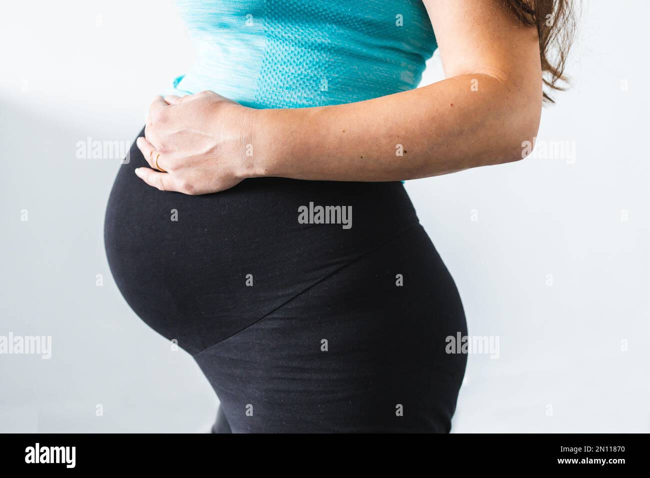 pregnant woman touching her bump in the latest stage of pregnancy, mid ...