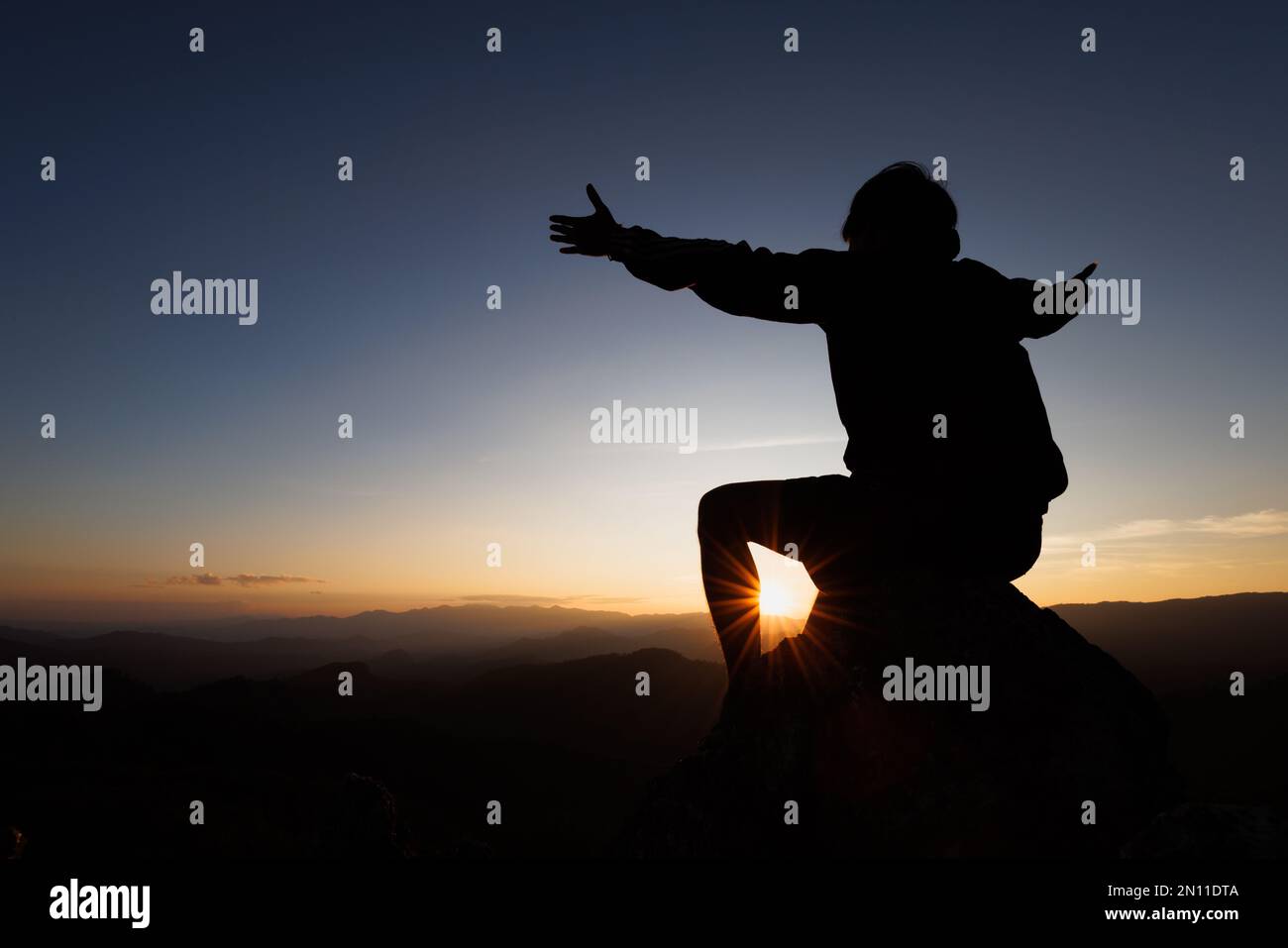 Silhuette Young Woman praying on the mountain, arms outstretched ...