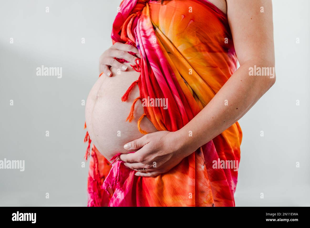 pregnant woman touching her bump in the latest stage of pregnancy, mid ...