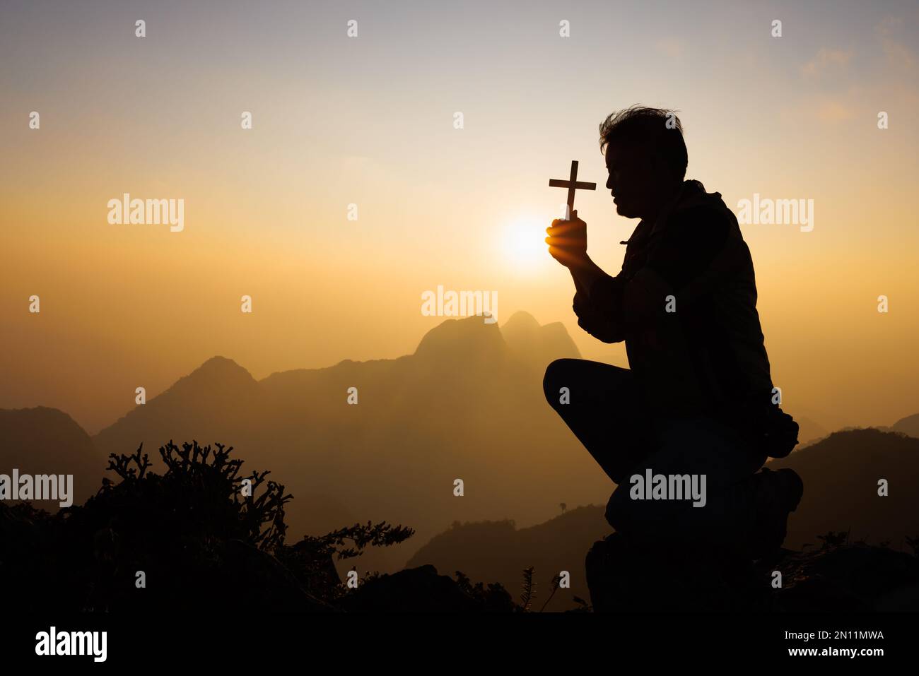 Silhouette of christian man hand praying, man holding a crucifix ...