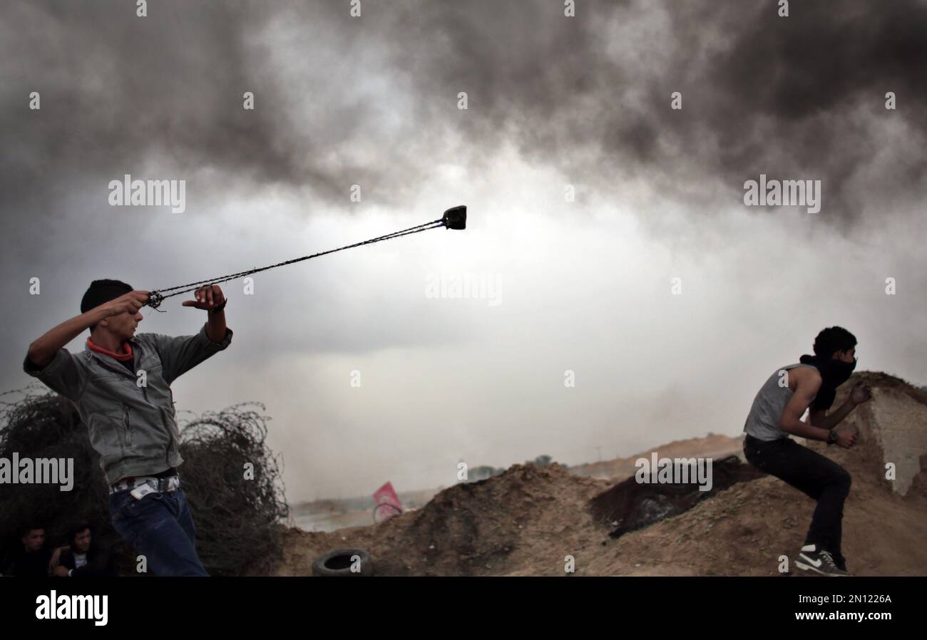 A Palestinian protester hurls stones using a sling shot during clashes ...