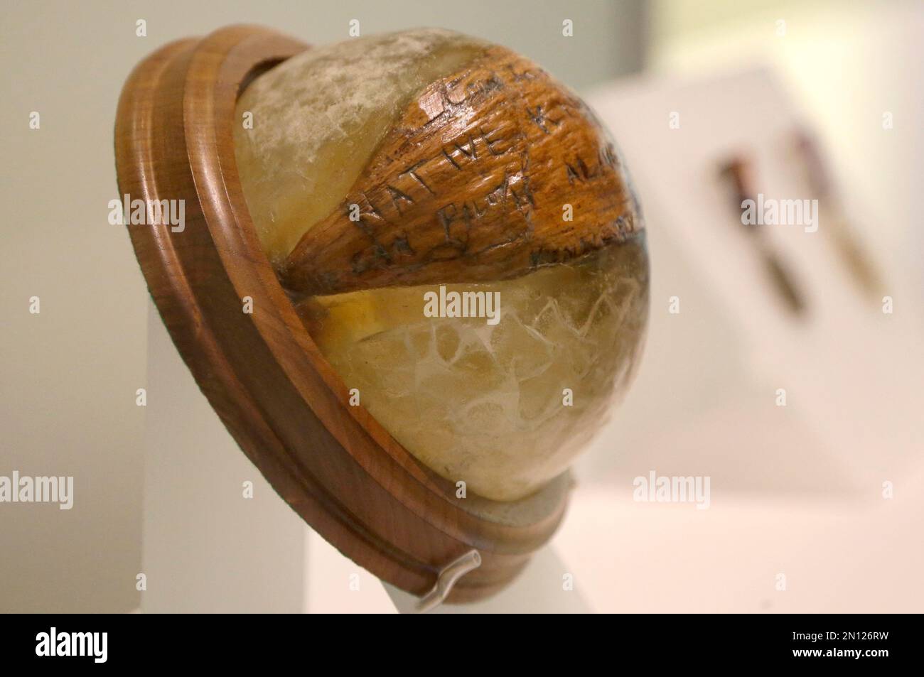 A coconut husk with a message carved into it rests in a display case in ...