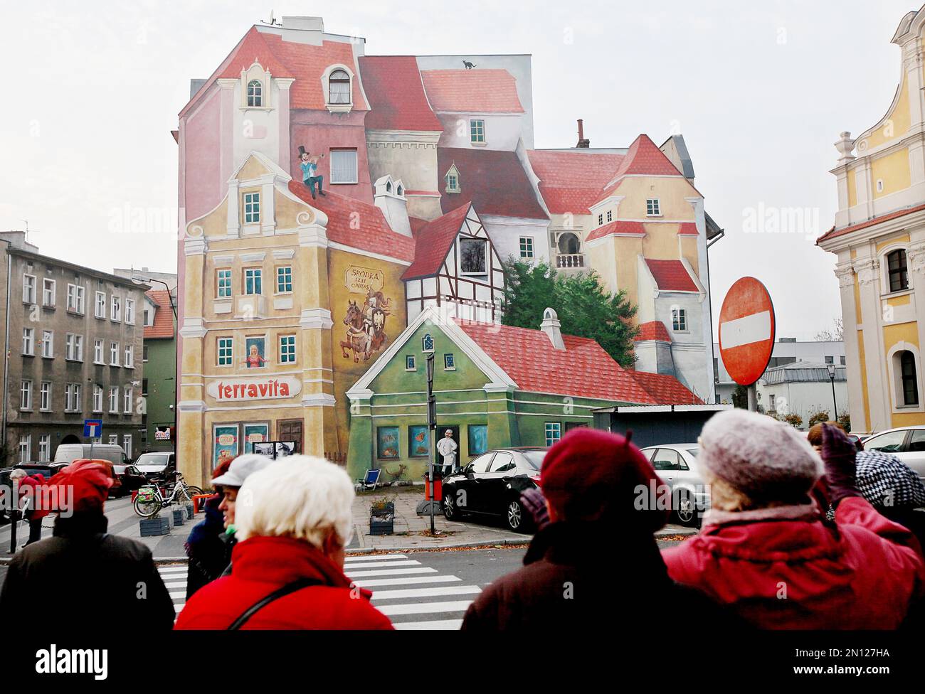 People admire a new mural in the oldest district of Srodka in Poznan ...