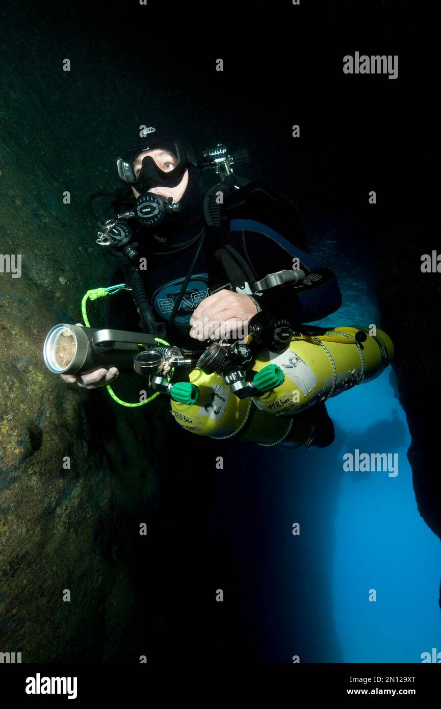 Diver dives into entrance of underwater cave with special equipment ...