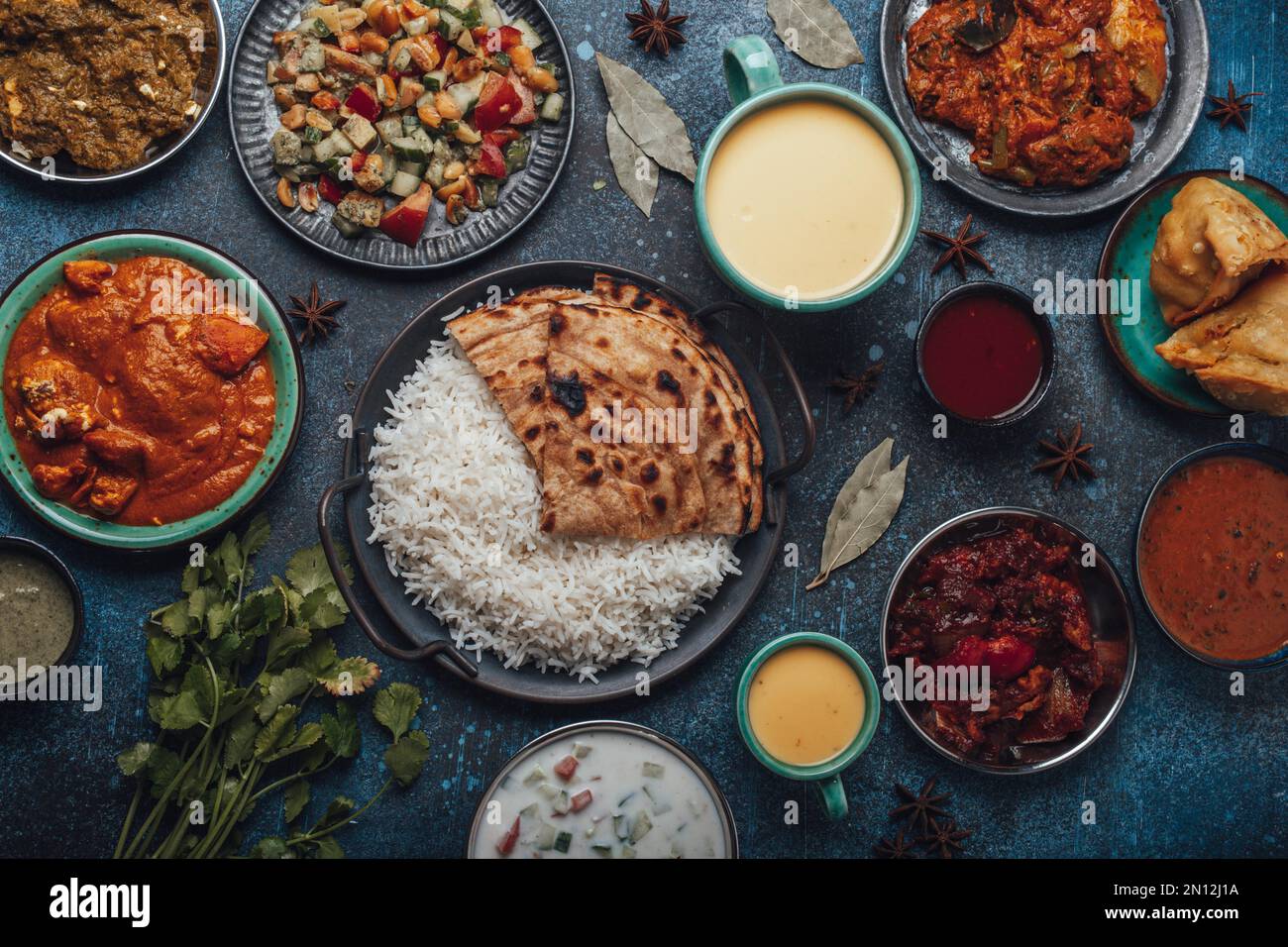Assorted Indian ethnic food buffet on rustic concrete table from above ...