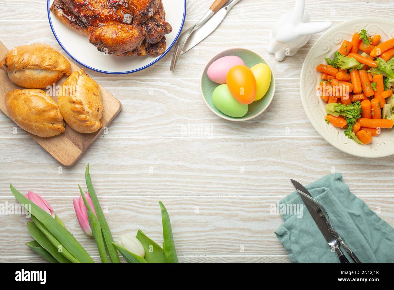 Easter food on white rustic table: pastel colored eggs, roasted chicken ...