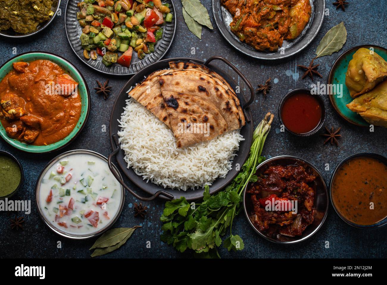 Assorted Indian ethnic food buffet on rustic concrete table from above ...
