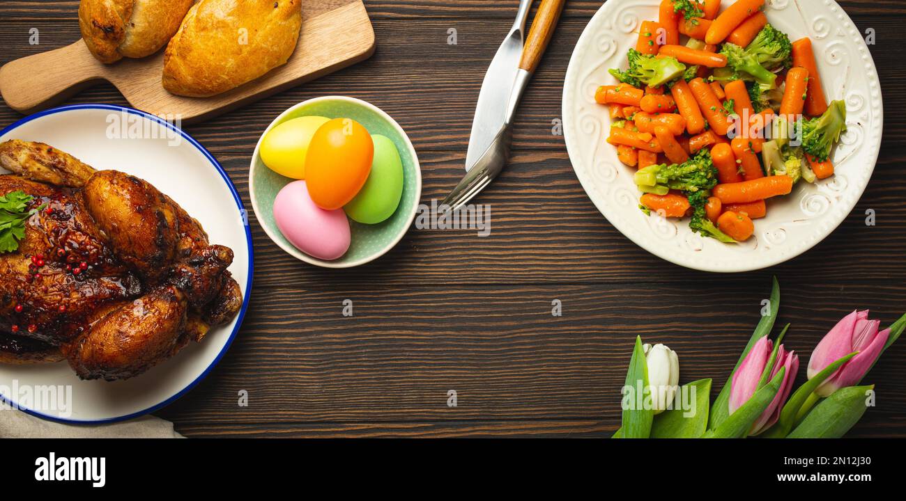 Easter food on dark rustic table: pastel colored eggs, roasted chicken ...