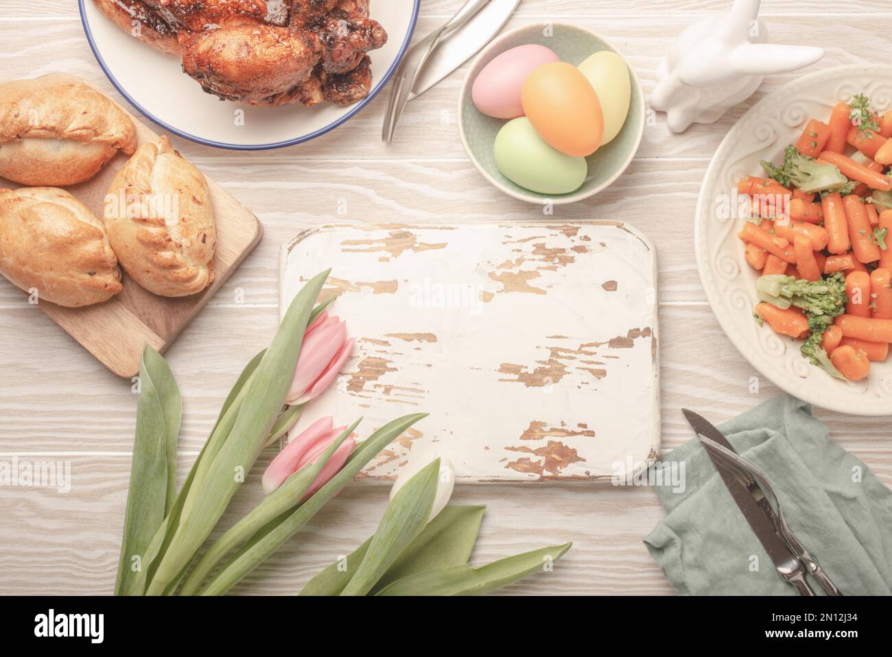 White empty wooden cutting board and Easter food on kitchen table ...