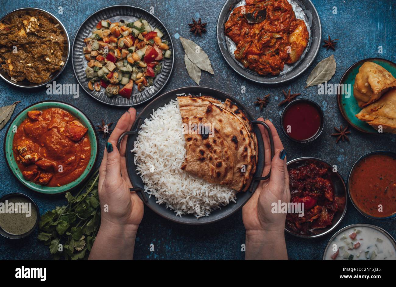 Assorted Indian ethnic food buffet on rustic concrete table from above ...