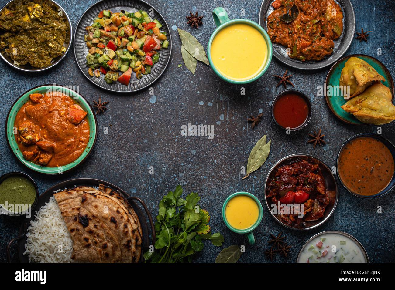 Indian ethnic food buffet on concrete table from above: curry, samosa ...