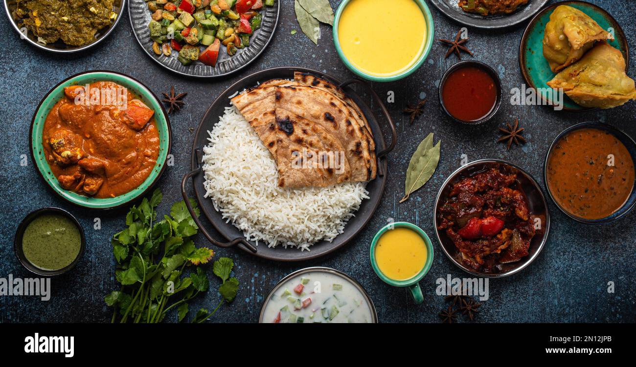 Assorted Indian ethnic food buffet on rustic concrete table from above ...