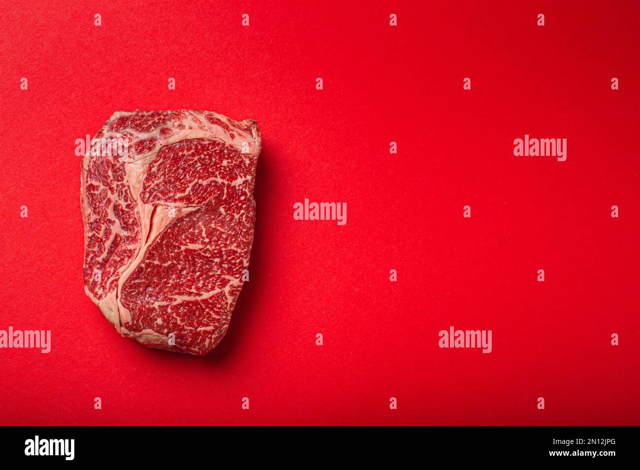 Raw meat beef prime cut steak Ribeye on clean red background from above ...