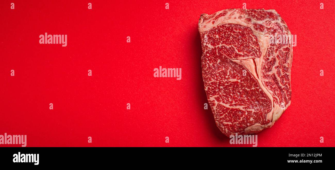 Raw meat beef prime cut steak Ribeye on clean red background from above ...