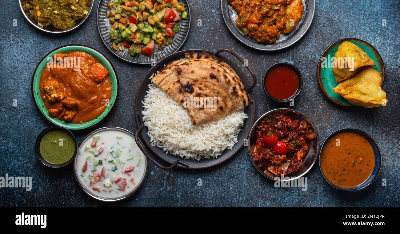 Assorted Indian ethnic food buffet on rustic concrete table from above ...