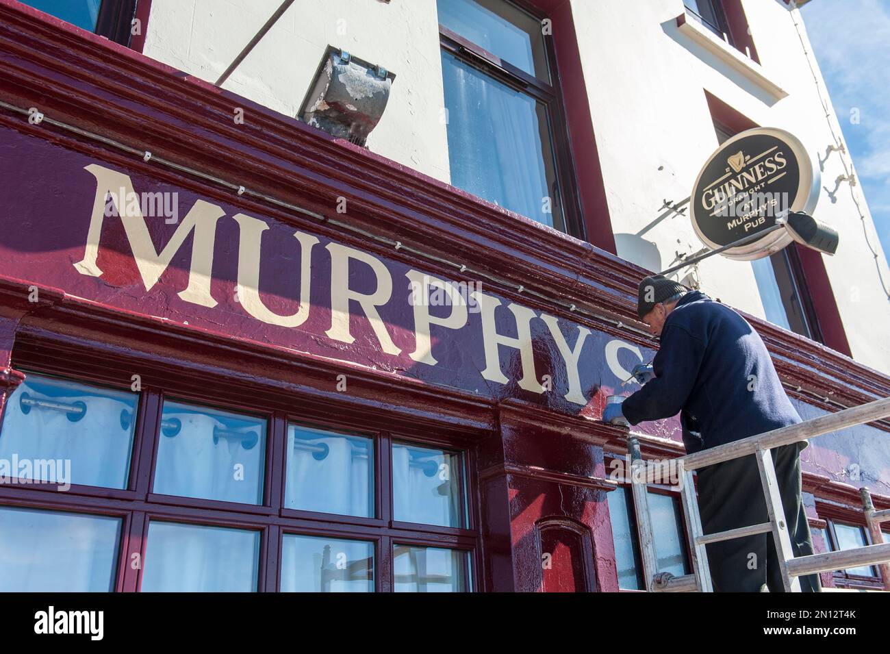 Painter, repaint, old man paints Pub Murphys, Guinness sign, Strand St ...