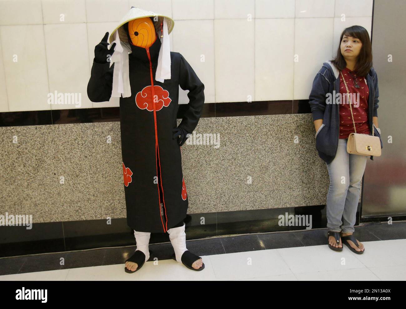 A woman watches a costume player, or cosplayer, poses for anime fans at ...