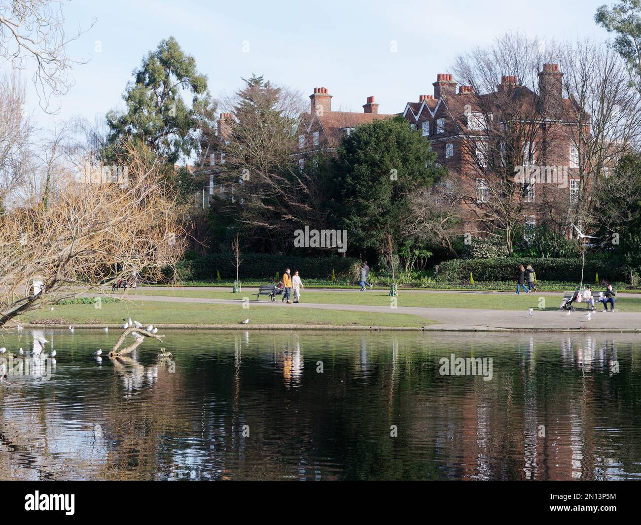 People walking along Regents Park with pond in foreground and a mansion ...