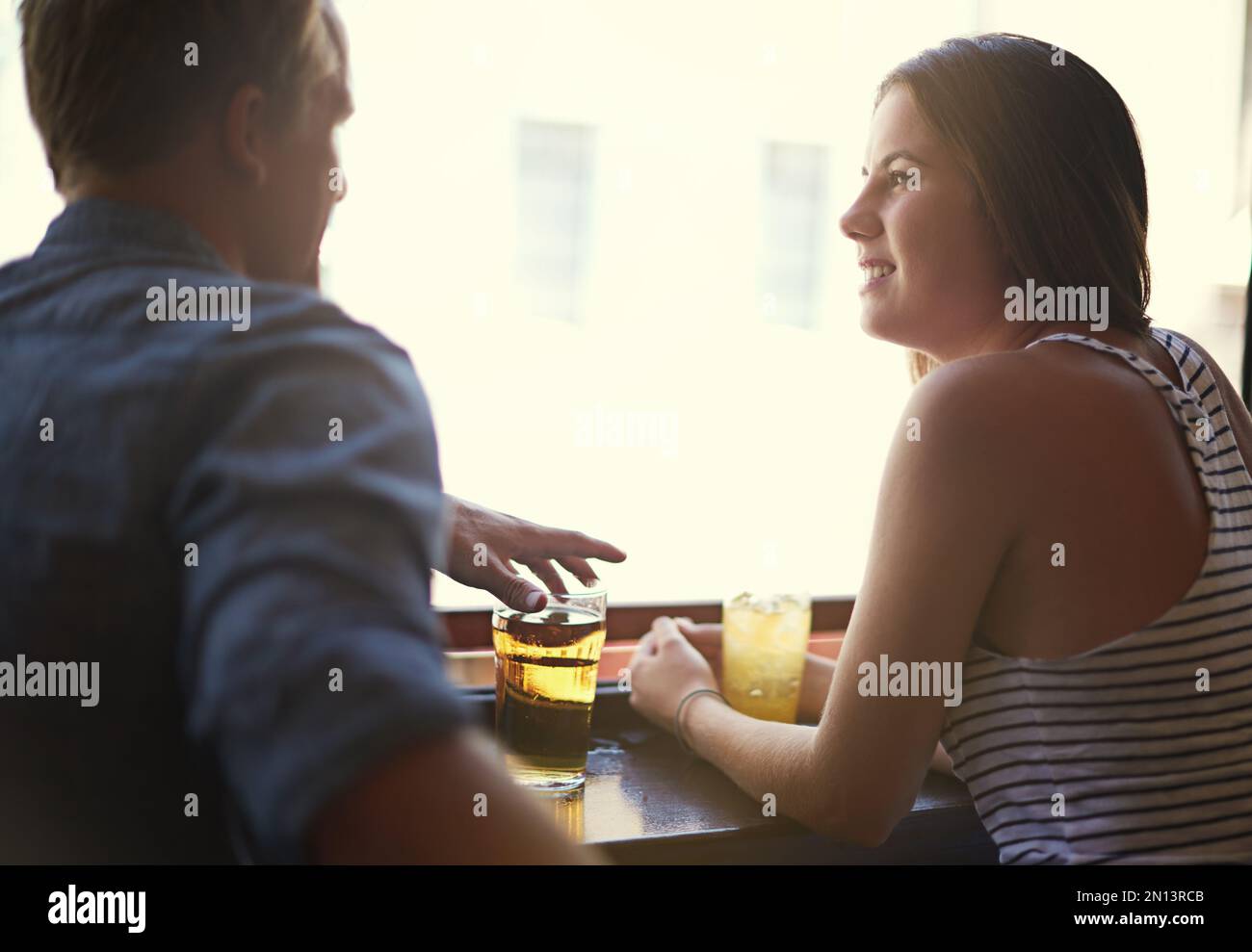 Sharing a drink and a laugh. a young couple talking together in a bar ...