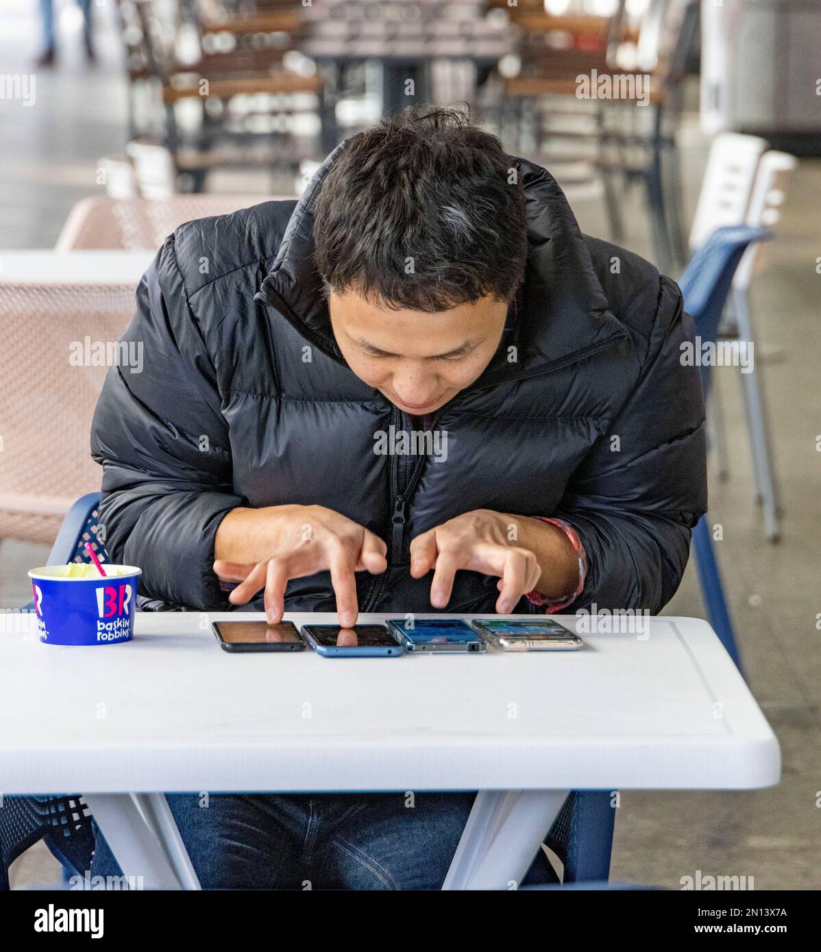 Japanese man playing or tapping four phones at once possibly playing a ...