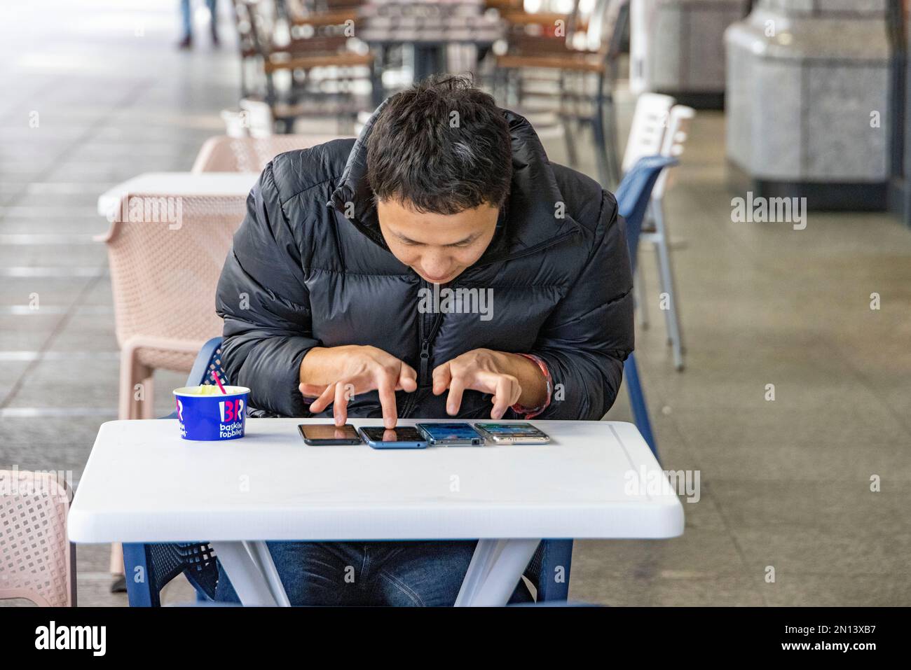 Japanese man playing or tapping four phones at once possibly playing a ...