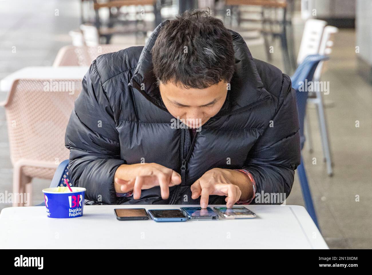 Japanese man playing or tapping four phones at once possibly playing a ...