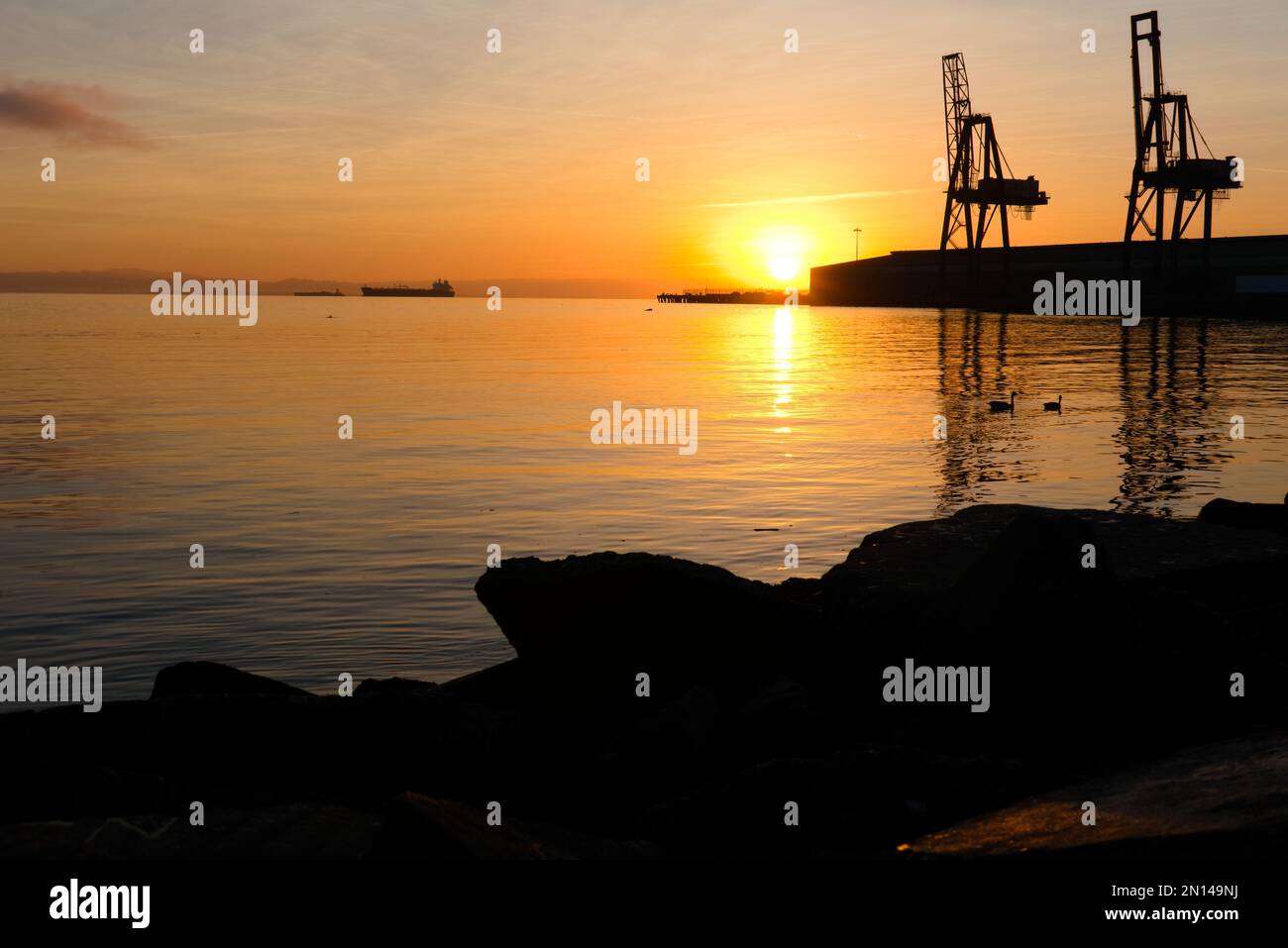 Large cargo ship to the left and container crane to the right during ...