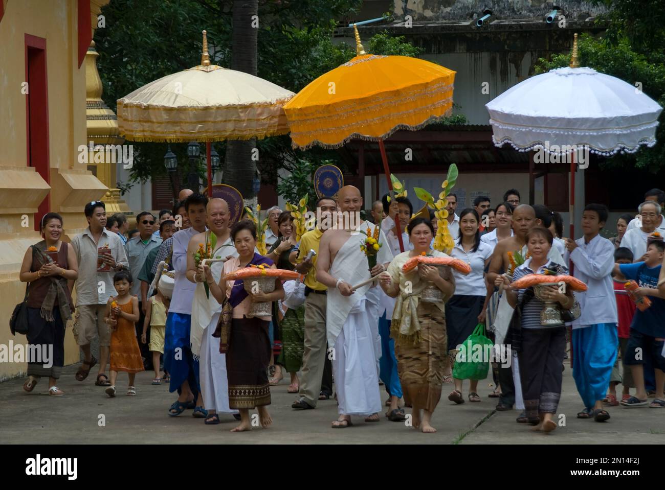 Novice monks in ceremony walking around temple, with family & friends ...